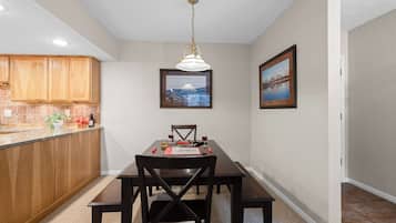 Uma sala de jantar com mesa de madeira, cadeiras e luminária pendente.