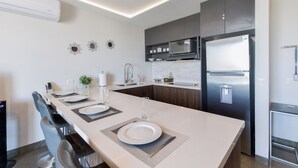 Uma cozinha moderna com ilha central, armários escuros e eletrodomésticos de aço inoxidável.