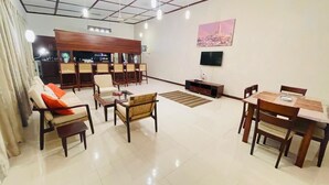 Uma sala ampla com sofá, cadeiras, mesa de jantar e televisão.