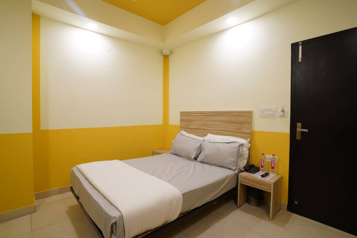Uma cama de solteiro com cabeceira de madeira em quarto com paredes amarelas e brancas.