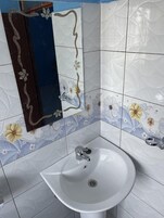 Um banheiro com uma pia branca, um espelho com borda floral e azulejos decorativos.