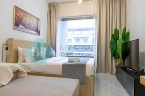 Quarto de hotel com duas camas, uma janela grande com cortinas, um quadro na parede e uma planta.
