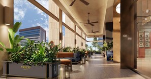 Um hall de hotel moderno com área de estar central, plantas em vasos e um bar.