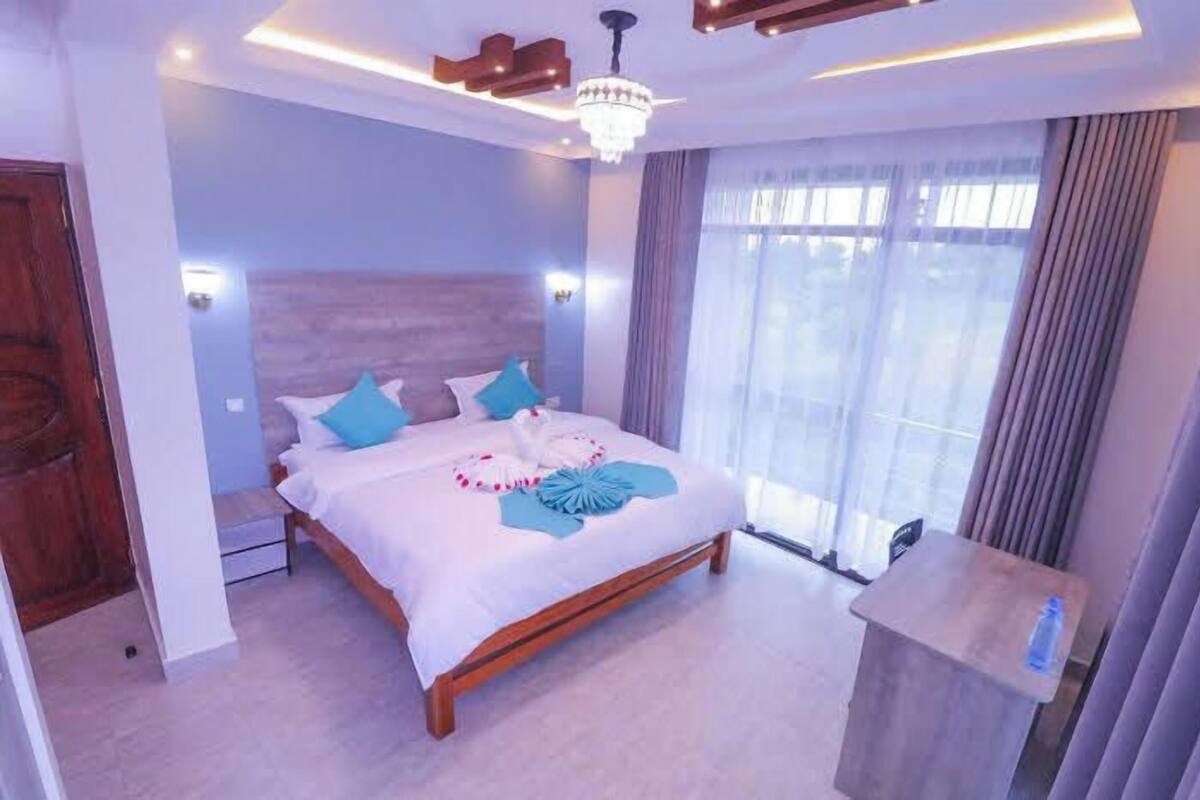 Quarto moderno com cama de madeira, um candelabro e uma janela grande com cortinas.