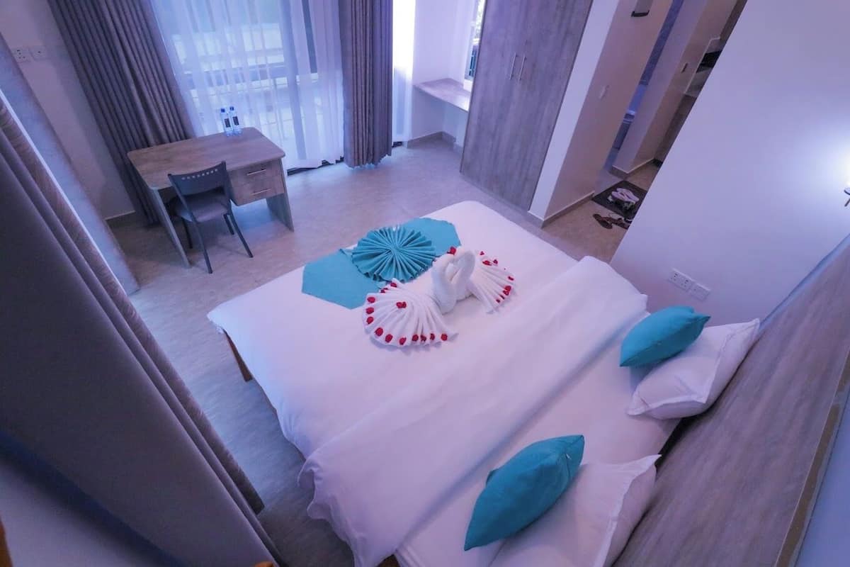 Quarto de hotel com cama, escrivaninha e cadeira.