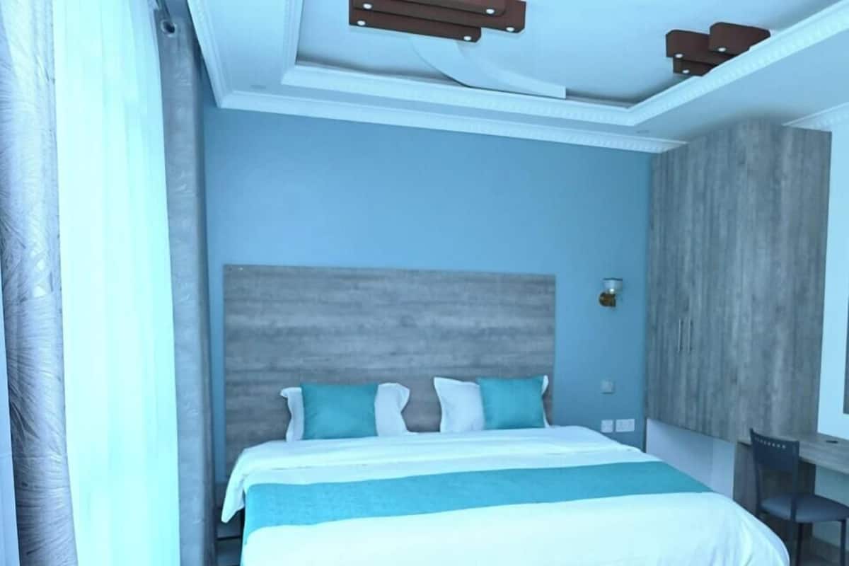 Quarto com cama, cabeceira, guarda-roupa e mesa de cabeceira.