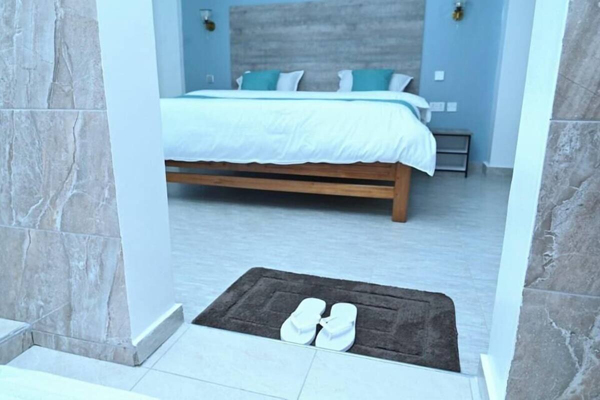 Quarto com cama, almofadas e mesa de cabeceira.