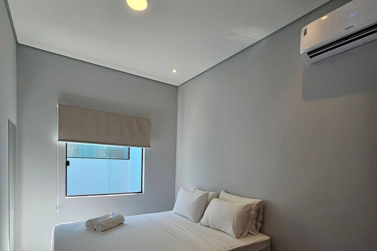 Quarto com cama, janela com vista, ar condicionado e mesa de cabeceira.