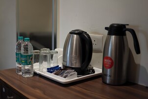Uma bancada de cozinha com uma cafeteira, garrafas de água e uma garrafa térmica.