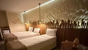 Quarto moderno com uma cama grande, duas mesas de cabeceira, uma cadeira e uma parede com textura diferenciada.