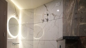 Uma casa de banho moderna com parede de mármore, espelho redondo, lavatório e sanita.