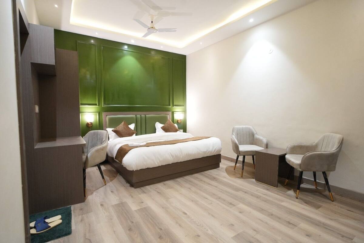 Quarto moderno com uma cama grande, duas cadeiras, uma escrivaninha e uma televisão.