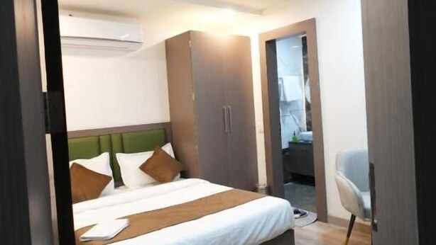 Quarto de hotel moderno com uma cama grande, um guarda-roupa, uma escrivaninha e uma cadeira.