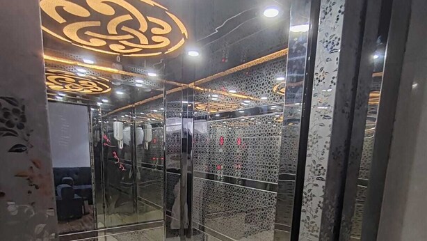 Um elevador moderno com painéis de vidro e parede com padrão geométrico.