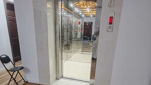 Um elevador com porta de vidro, um telefone e uma luz de emergência vermelha.