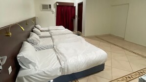 Quarto de hotel com uma cama grande, um ventilador de teto, cortina vermelha e piso de azulejos.