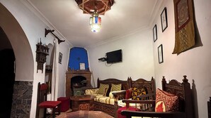 Quarto tradicional com cama de madeira, lareira, lustre e mesa de jantar.