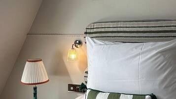 Quarto com cama, luminária, luz embutida na parede, quadro e decoração em forma de estrela.
