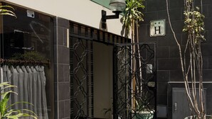 Pátio com entrada gradeada, plantas em vasos e piso de azulejos.