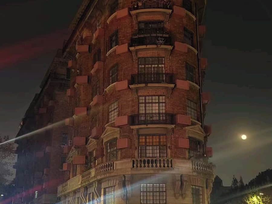 Um edifício de vários andares com fachada curva, grandes janelas e uma entrada destacada com arco.