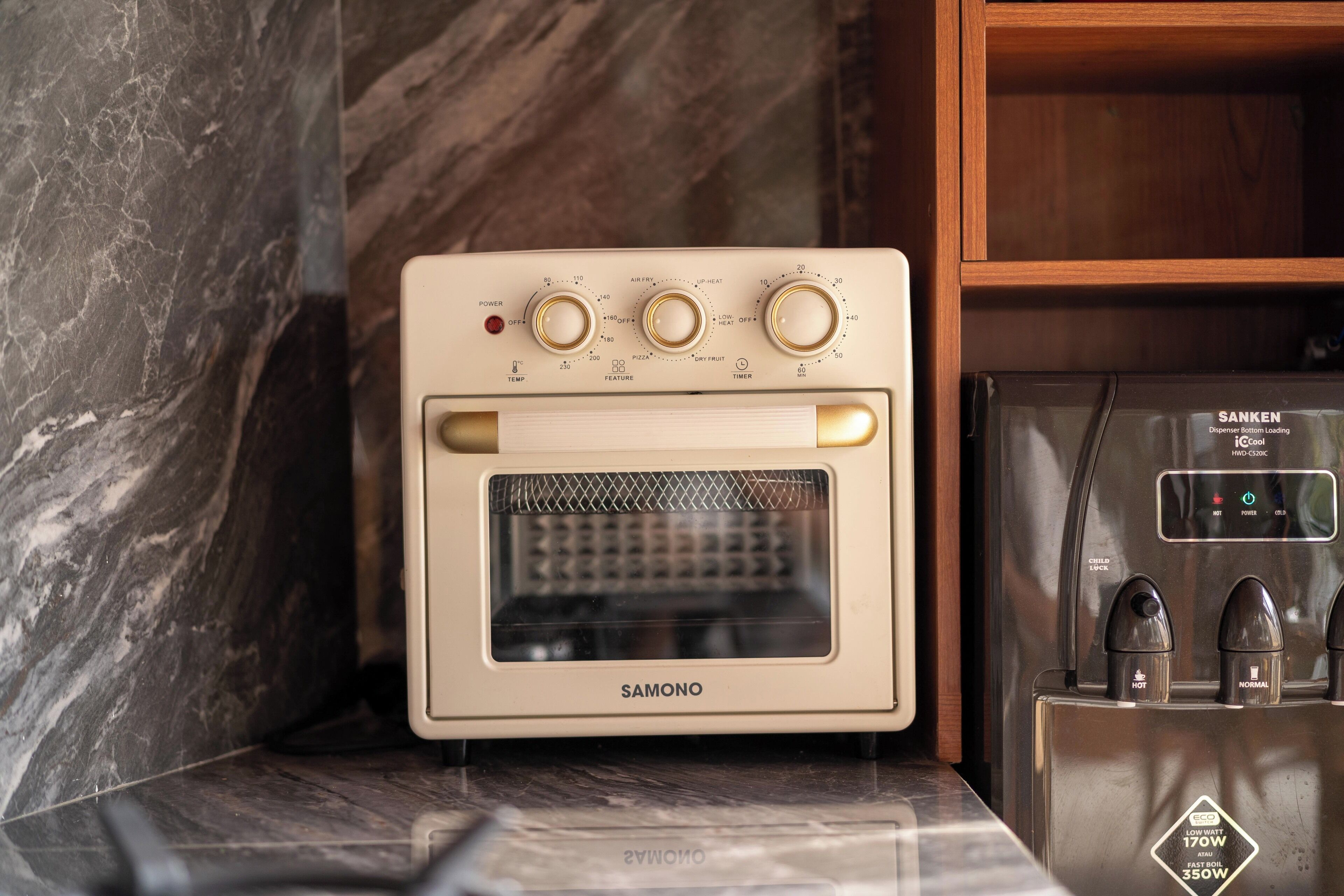 Um forno Samono antigo com botões de controle, uma grade embutida e um refrigerador de aço inoxidável com dispensador de água.