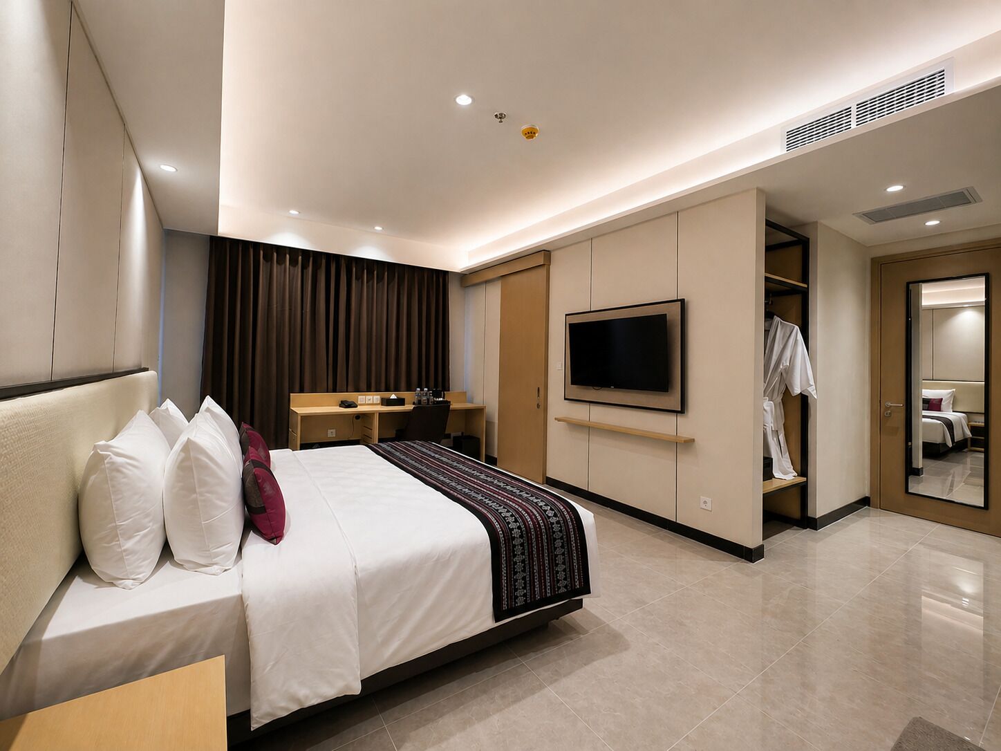 Quarto de hotel moderno com cama, escrivaninha, televisão e guarda-roupa.