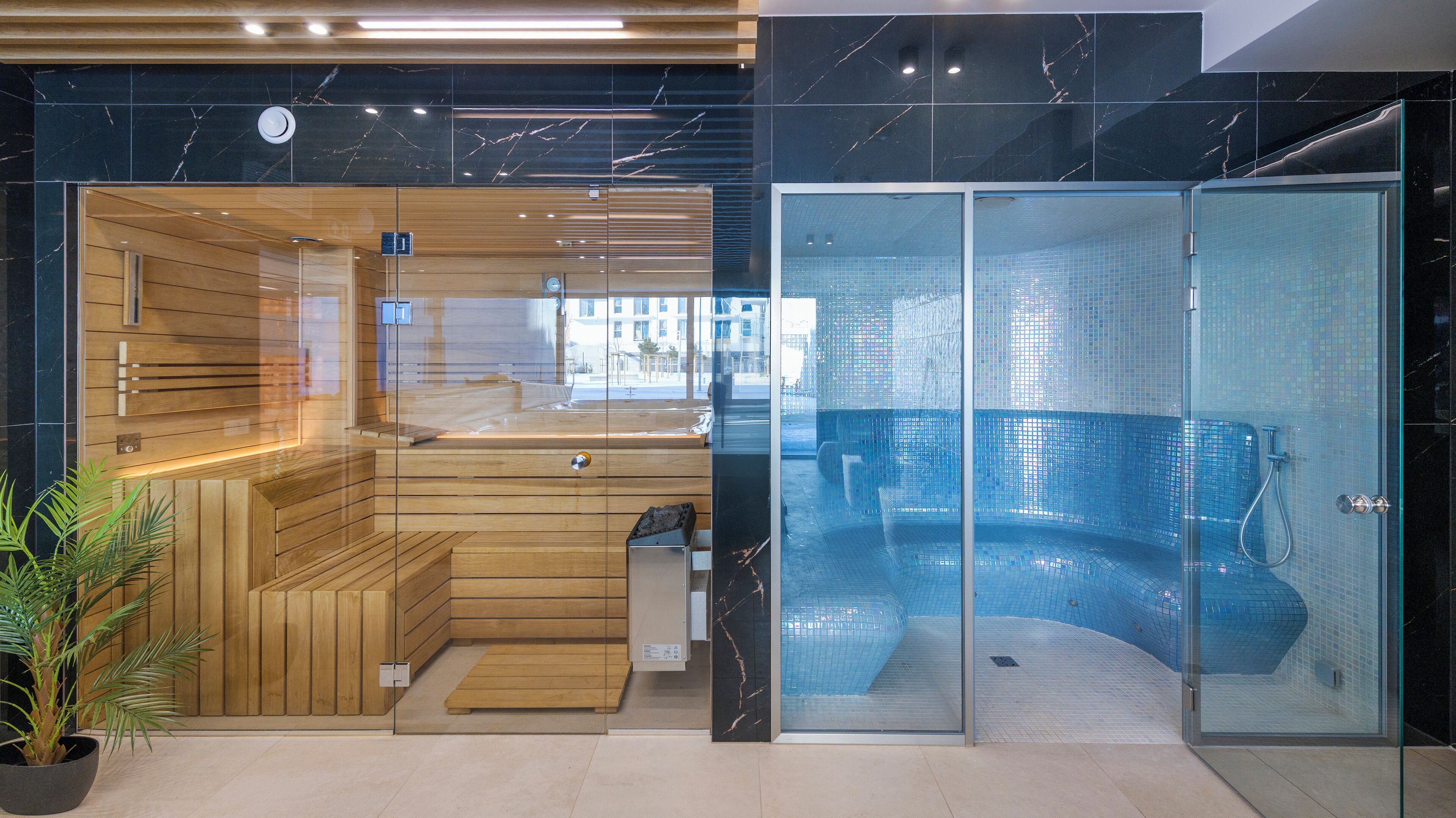 Uma área de spa moderna com sauna de madeira, hidromassagem em vidro e espaço para chuveiro revestido em azulejos.