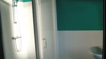 Um chuveiro com porta de vidro, uma pia branca e um chão revestido de azulejos.