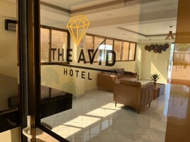 Interior de hotel com balcão de recepção, sofá e mesa de centro.