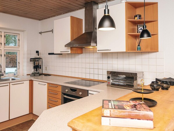 Cozinha moderna com armários brancos, cafeteira, torradeira e bancada de madeira.