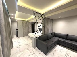 Uma sala de estar moderna com um sofá seccional, piso de mármore e um elemento decorativo geométrico.