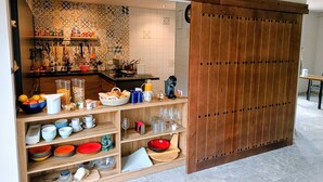 Cozinha com bancada de madeira, prateleiras com louças e um revestimento de parede estampado.