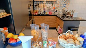 Uma bancada de cozinha com itens de café da manhã, incluindo frutas, cereais e pão.