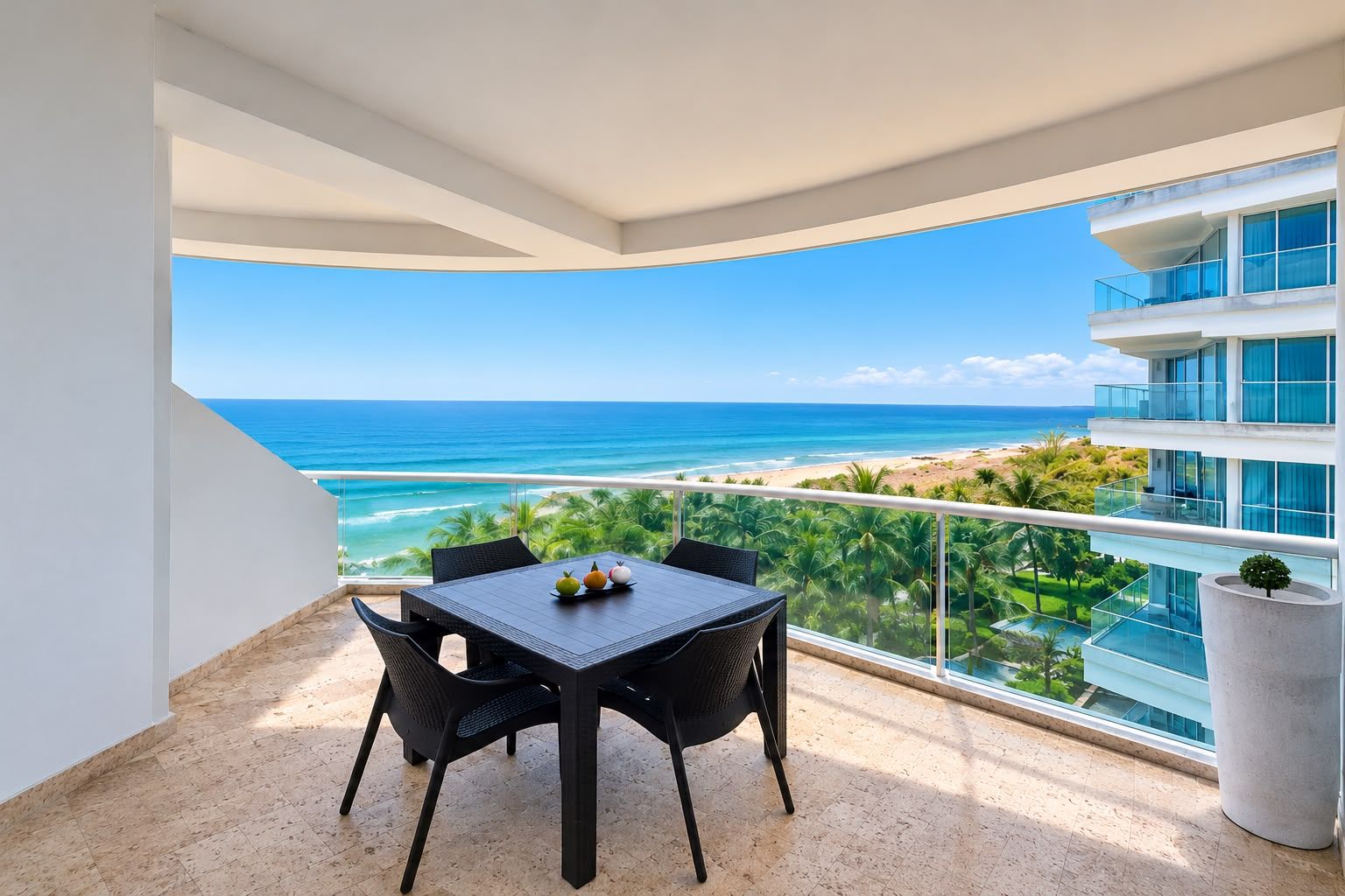 Varanda com mesa e cadeiras, com vista para uma praia e oceano.