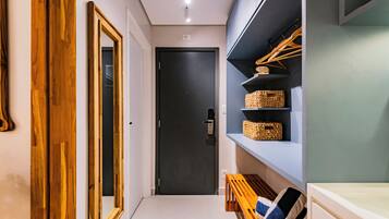 Um corredor com porta de madeira, um banco e prateleiras com cestos.
