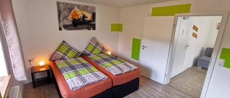 Uma cama de casal com um cobertor listrado, um abajur e um quadro pendurado na parede.