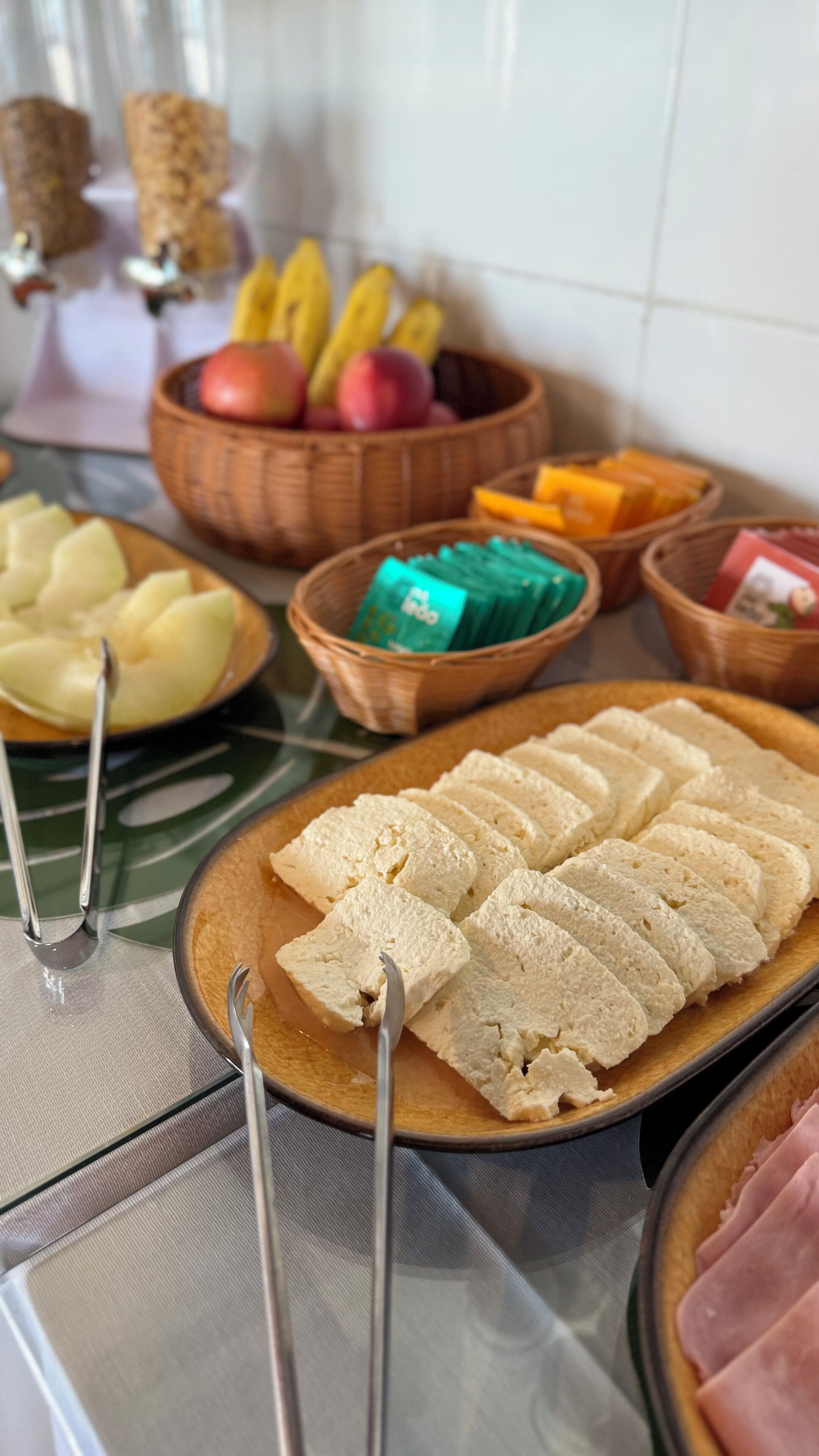 Uma bancada de cozinha com diversos alimentos, incluindo pão fatiado, frutas e acompanhamentos.