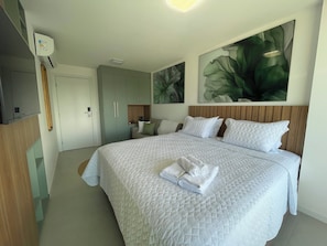 Quarto bem arrumado com uma cama grande, cabeceira de madeira e ar condicionado fixado na parede.