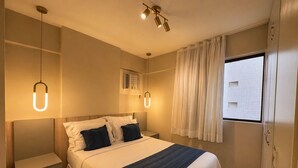 Quarto com cama, mesas de cabeceira, janela com cortinas e luminária no teto.