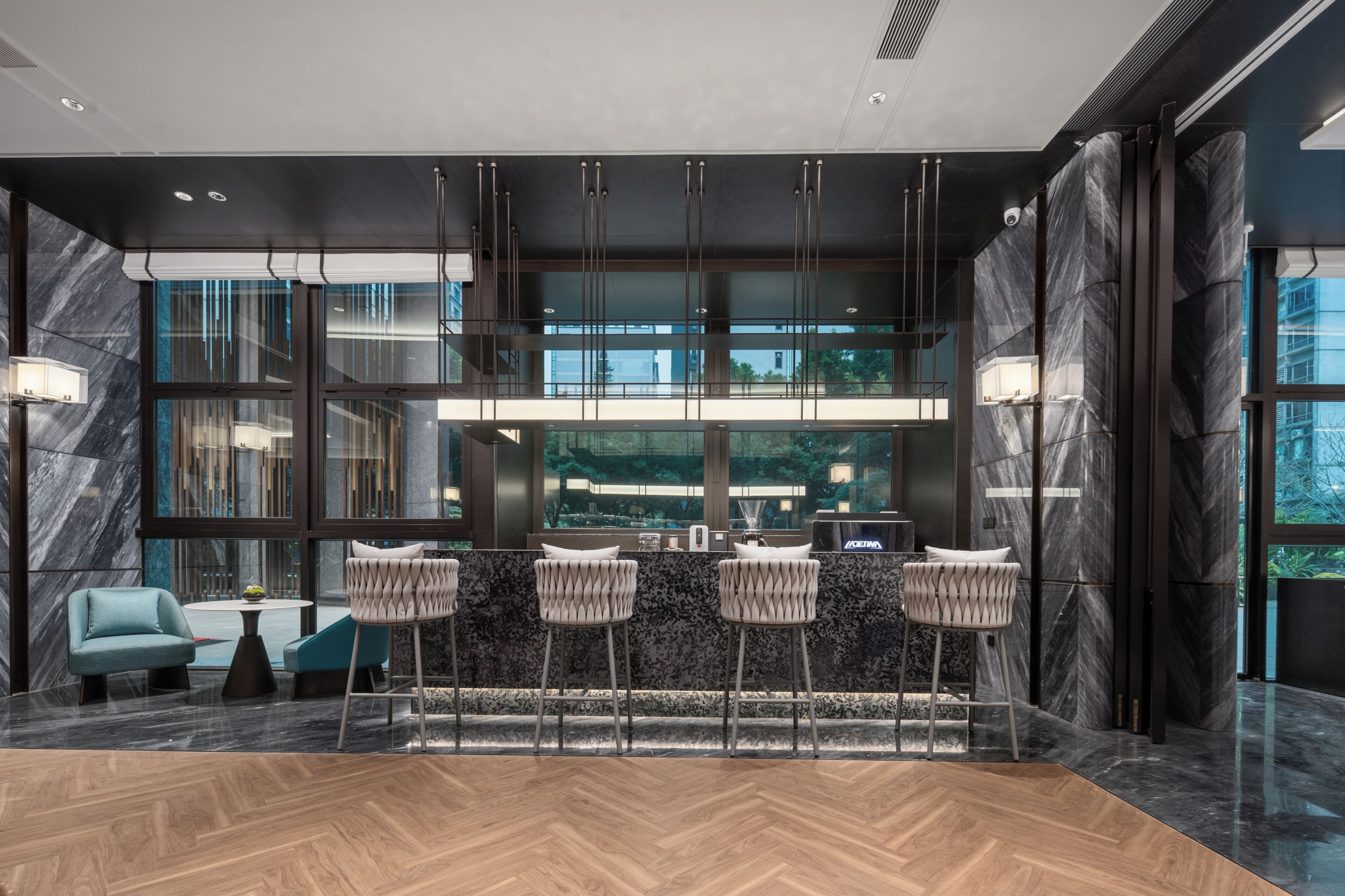Uma área de bar moderna com bancadas de mármore, banquetas e iluminação pendente.