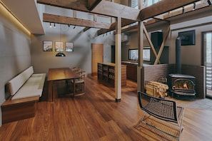 Um interior moderno com piso de madeira, um sofá, uma mesa de jantar e uma lareira.