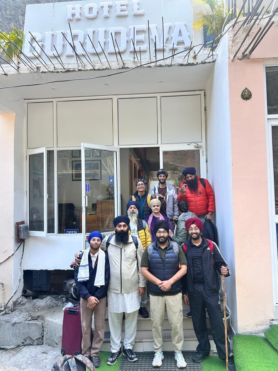 Um grupo de pessoas em frente a um edifício com uma placa que diz 'HOTEL'.