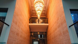 Uma escadaria de mármore com um candelabro, levando à entrada de um edifício moderno.