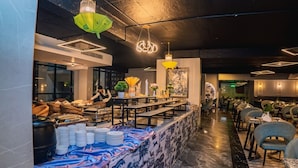 Um restaurante com um balcão comprido, várias áreas de estar e luminárias modernas.