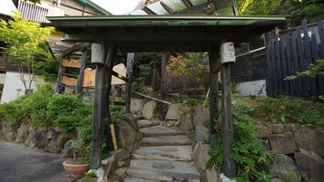 Uma estrutura tradicional japonesa de madeira com uma escadaria de pedra que a precede.