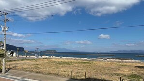 Vista costeira com um passeio calçado, área gramada e mar ao longe.