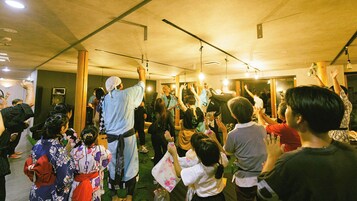 Um grupo de pessoas em uma sala com teto alto e dutos aparentes.