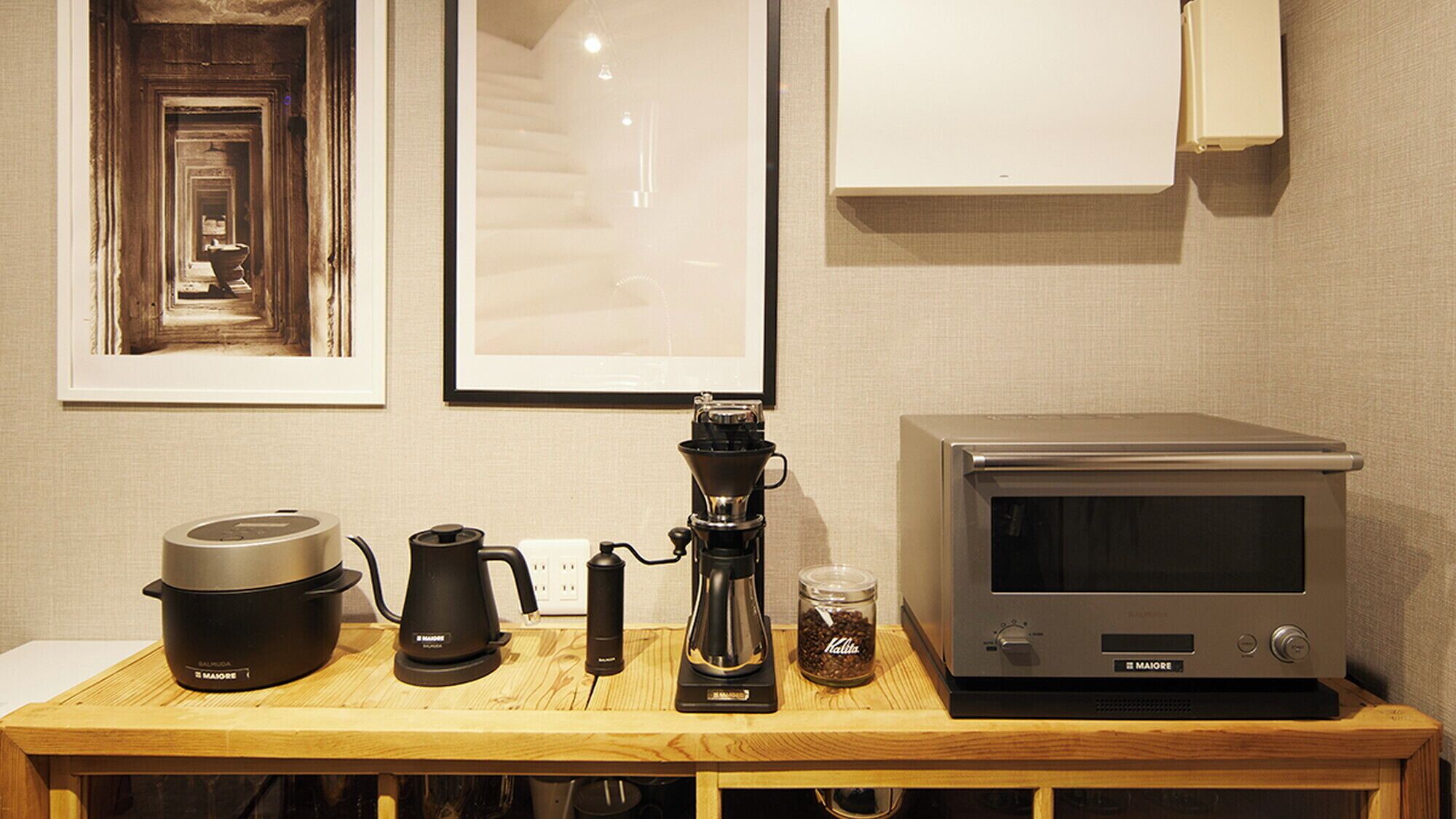 Uma bancada de cozinha com cafeteira, cozido lento, chaleira e micro-ondas.