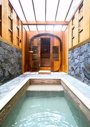 Uma área de spa com madeira, uma parede de pedra, uma porta de madeira e uma pequena piscina.