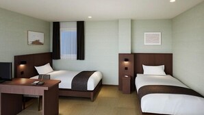 Quarto de hotel com duas camas, uma escrivaninha e uma televisão.